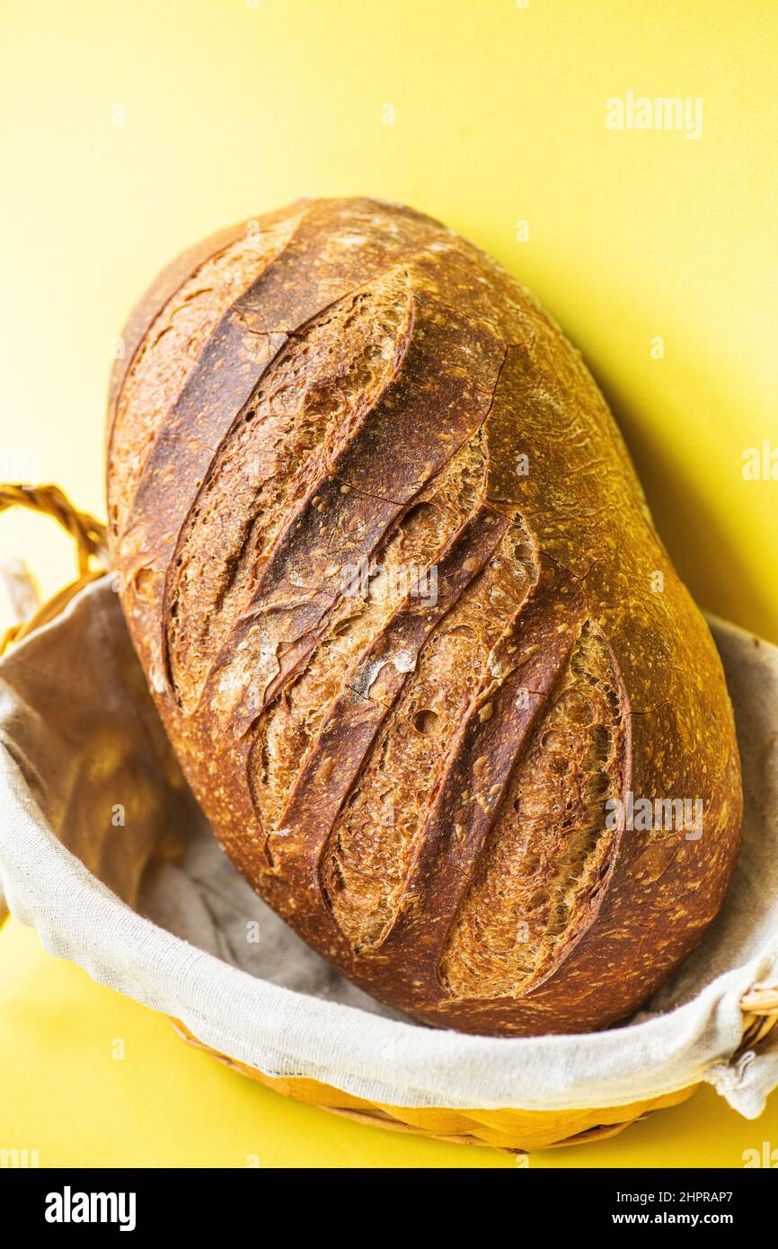 Homemade artisanal sourdough bread in a bread basket. Yellow background ...