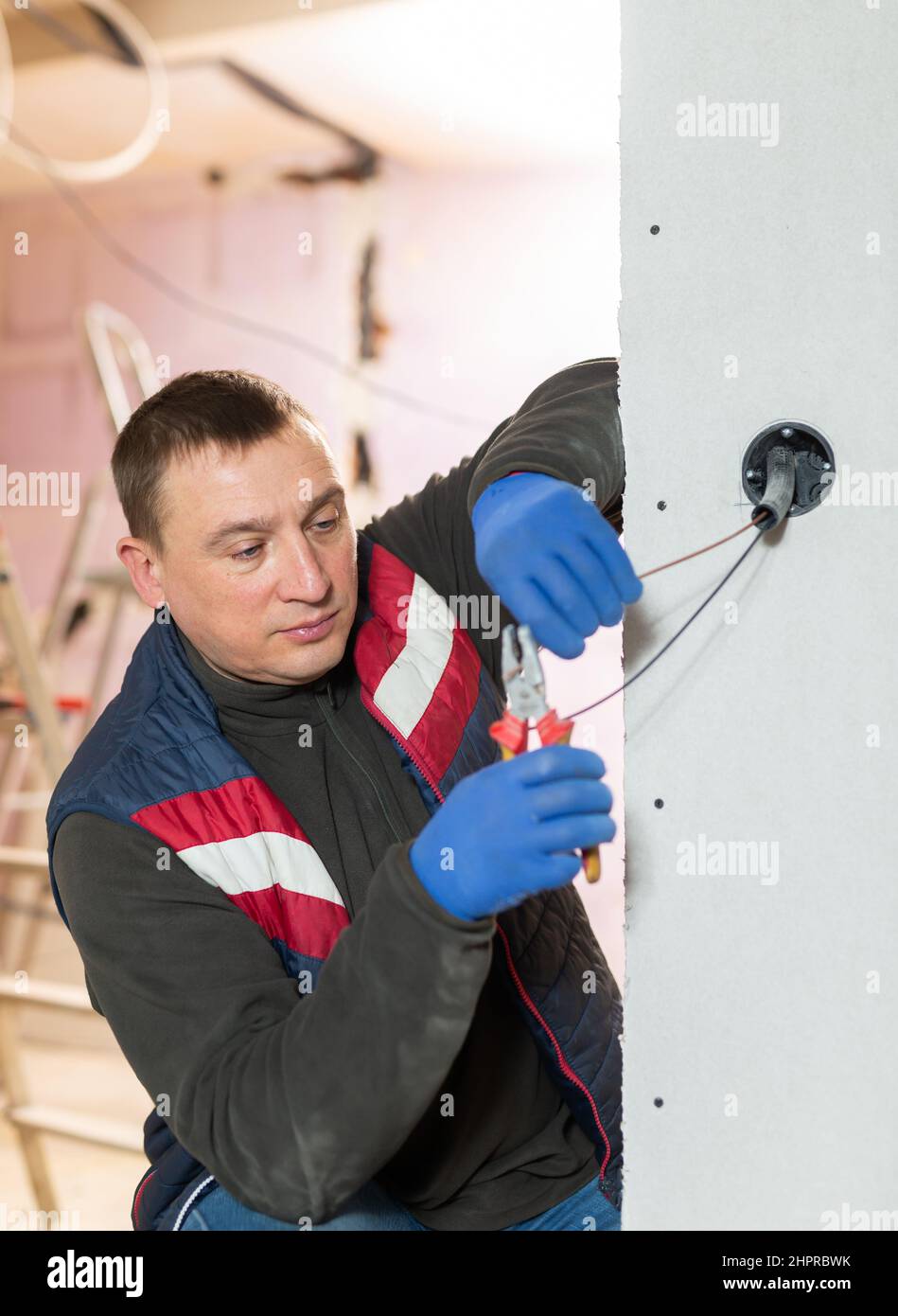 Professional builder engaged in electrical installation work at indoors ...