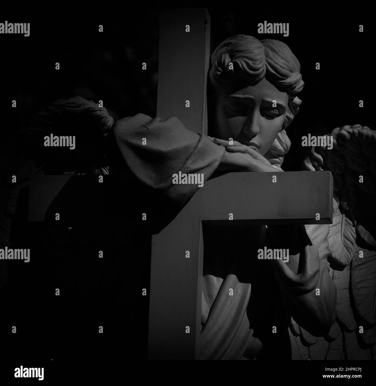 Black and white image of an ancient statue of angel with cross as ...