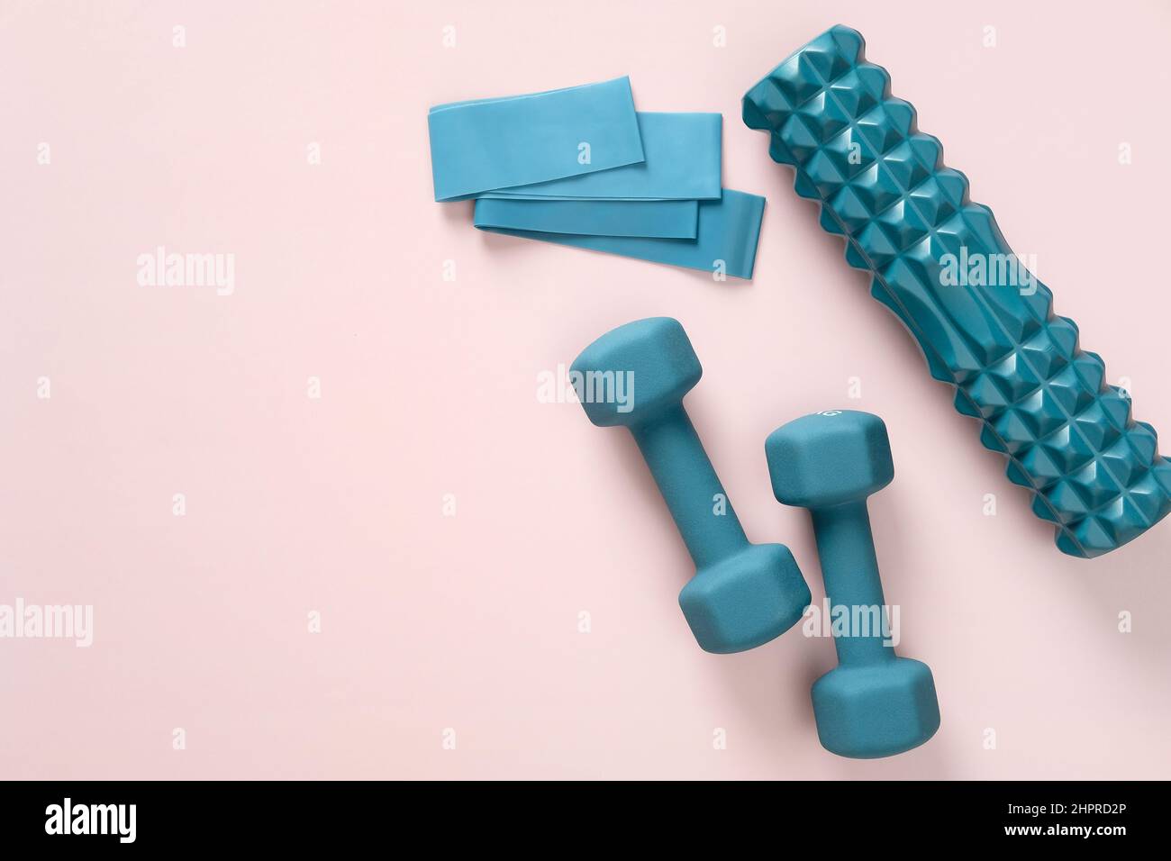 Dumbless, foam roller and fitness tapes on pastel pink background ...