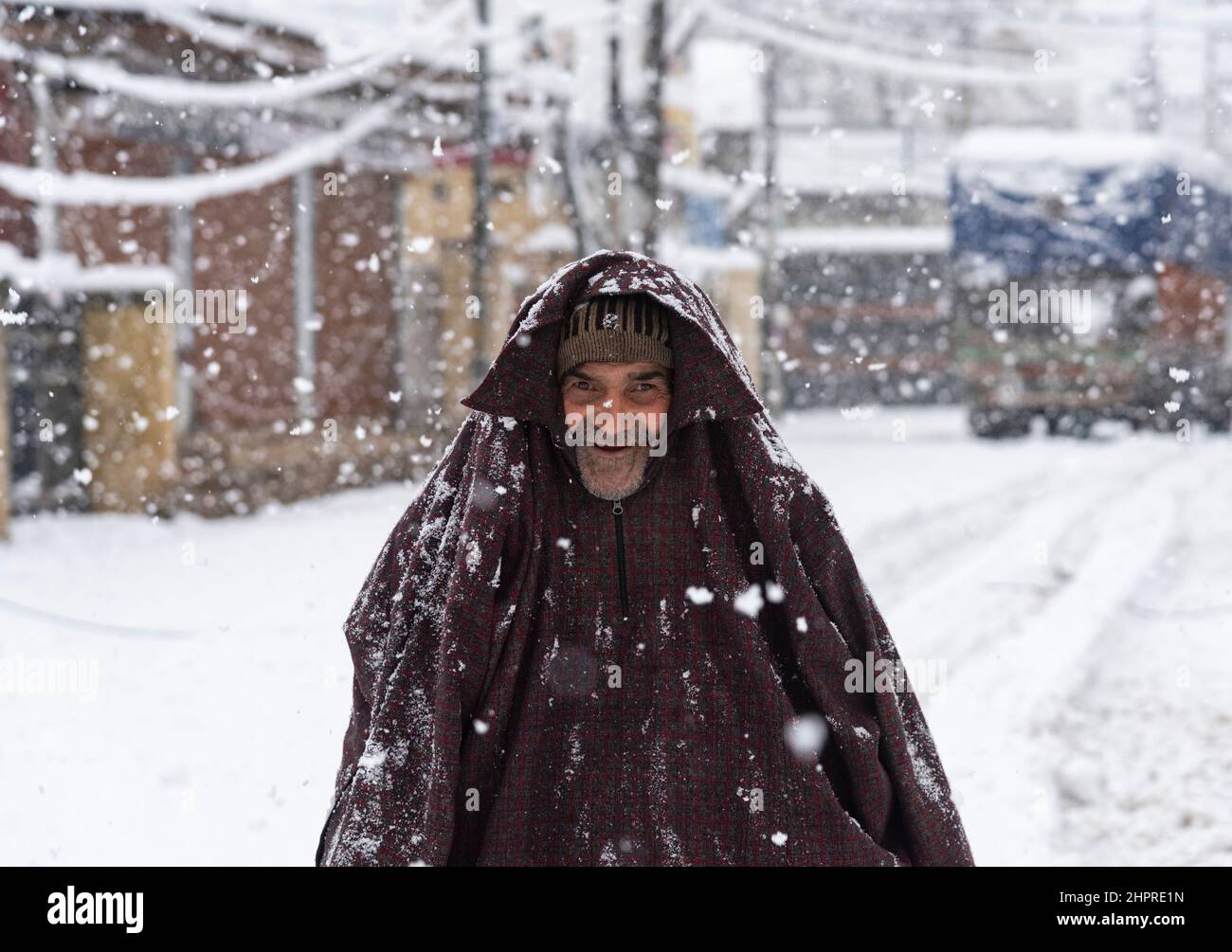 A man pulls his jacket over his head during heavy snowfall in Srinagar ...
