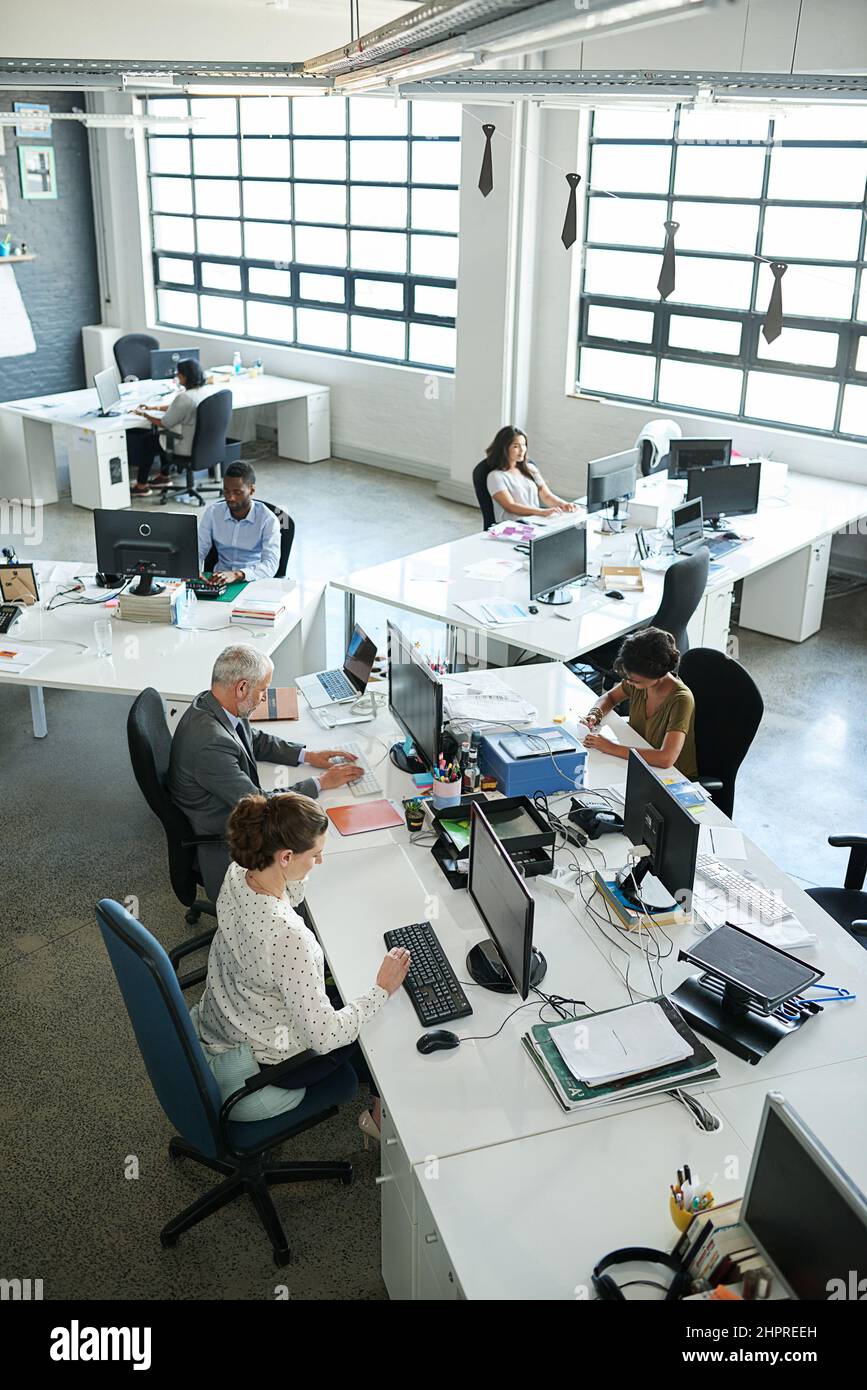 Everyones focused on their tasks. Shot of a group of coworkers sitting ...