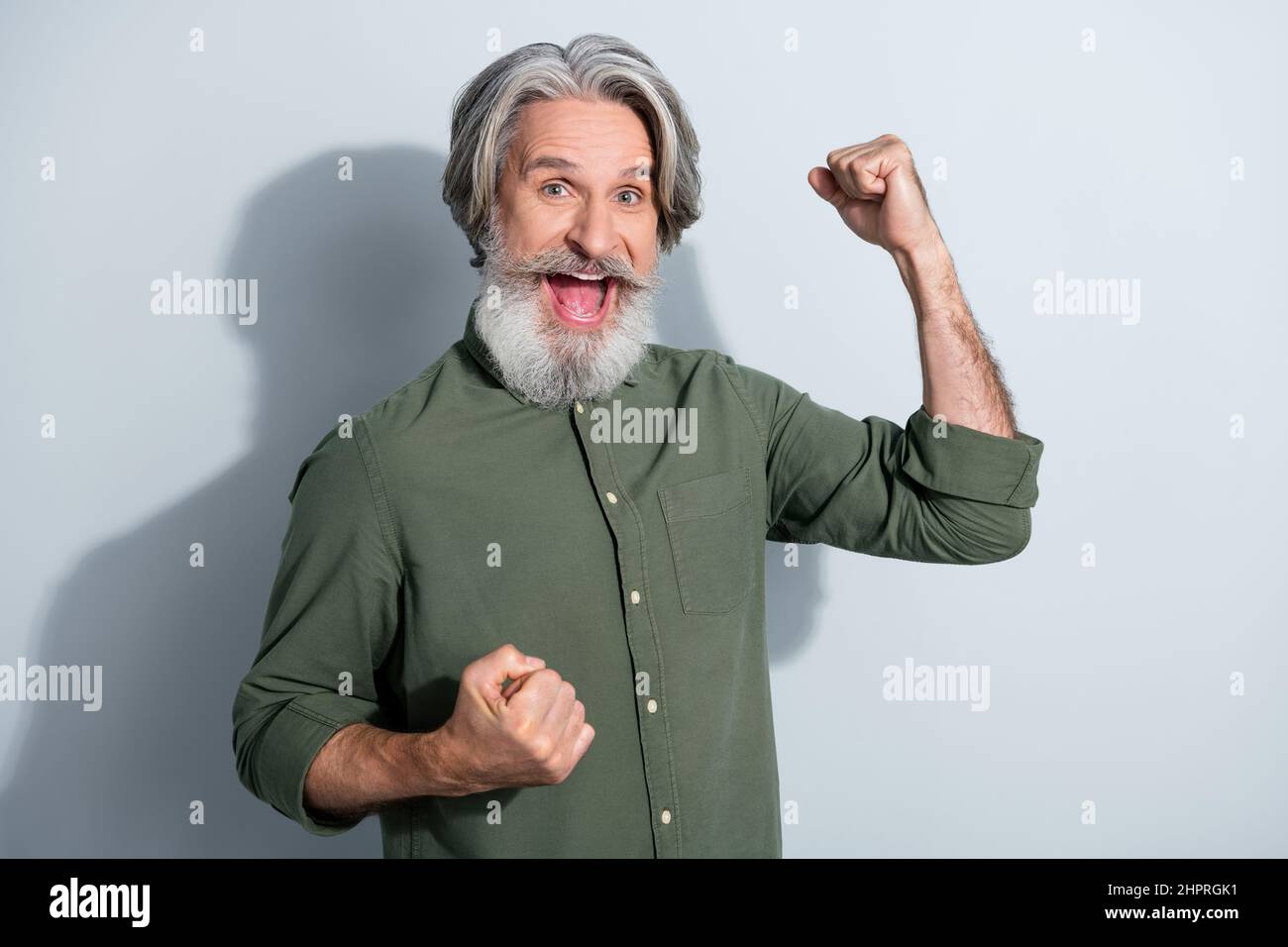 Portrait of attractive cheerful grey-haired man rejoicing having fun ...