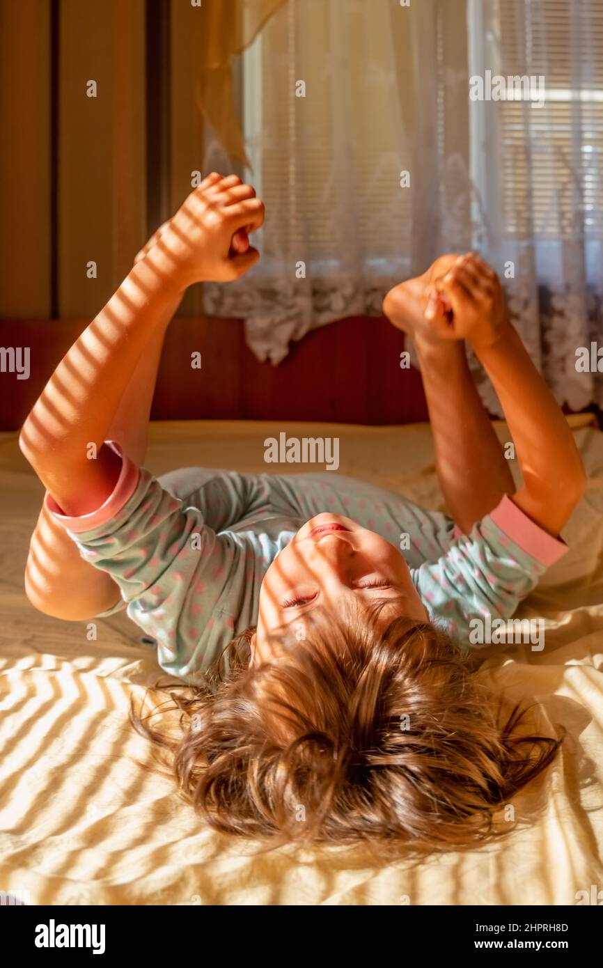 Close up portrait of very happy beautiful girl in pajamas lying upside ...