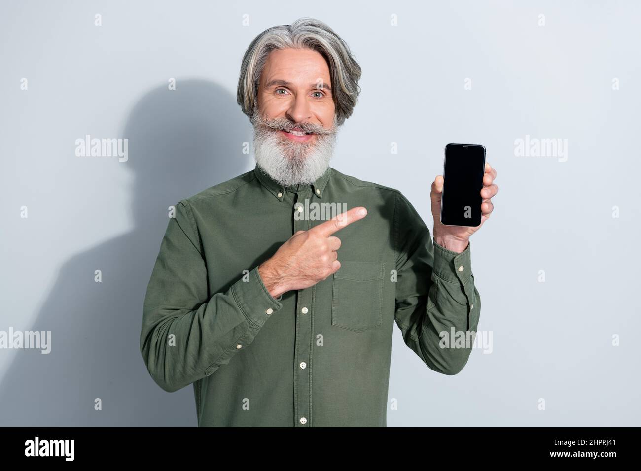 Portrait of handsome trendy cheery grey-haired man demonstrating gadget ...