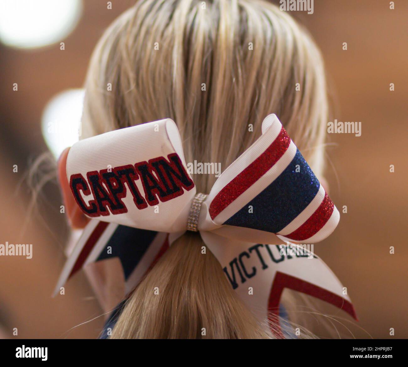 Big red white and blue bow on the back of a blond cheerleaders head ...