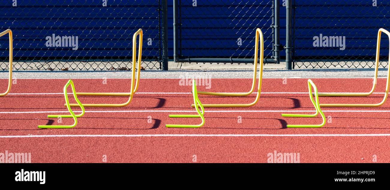 Small and larger yellow plasic hurdles in lanes on a track for speed ...