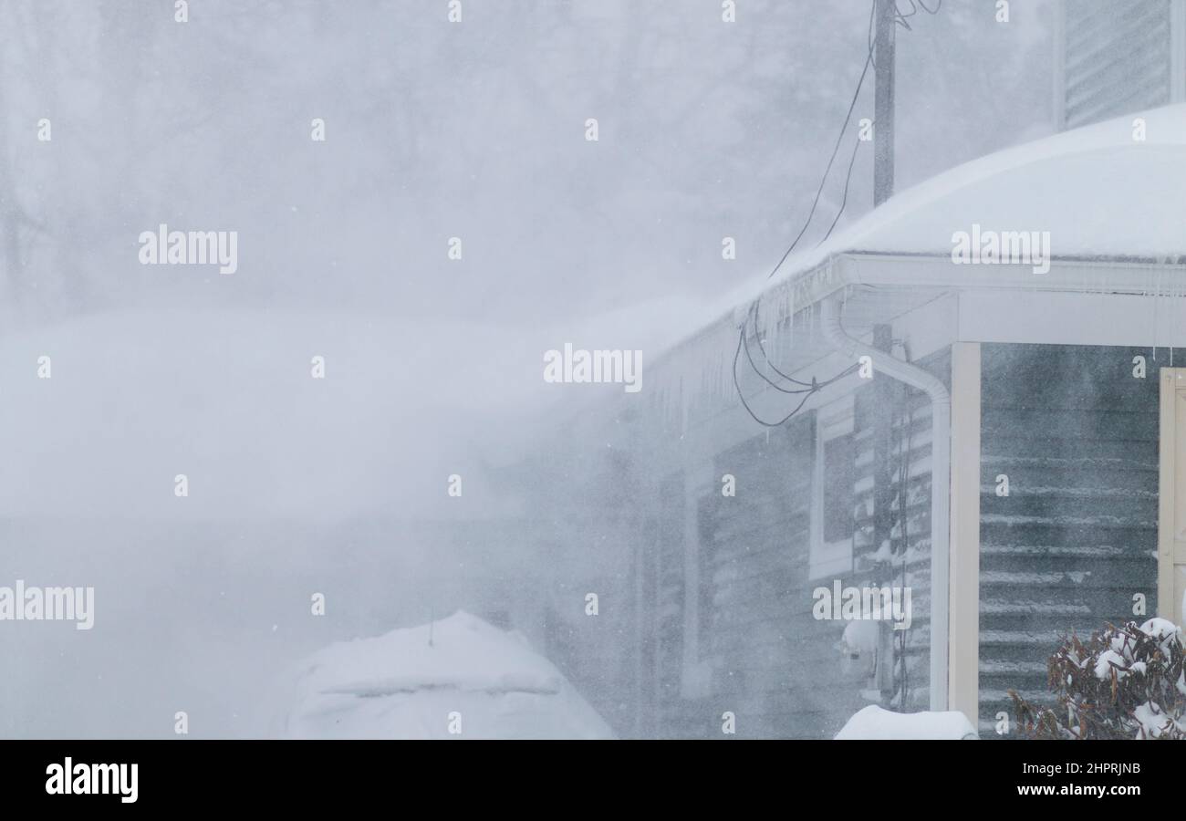 Snow blowing off a roof during a blizzard creating white out conditions ...