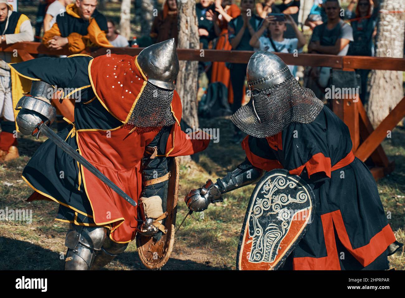 Two knights fight with swords. The knight's shield depicts a black wolf ...