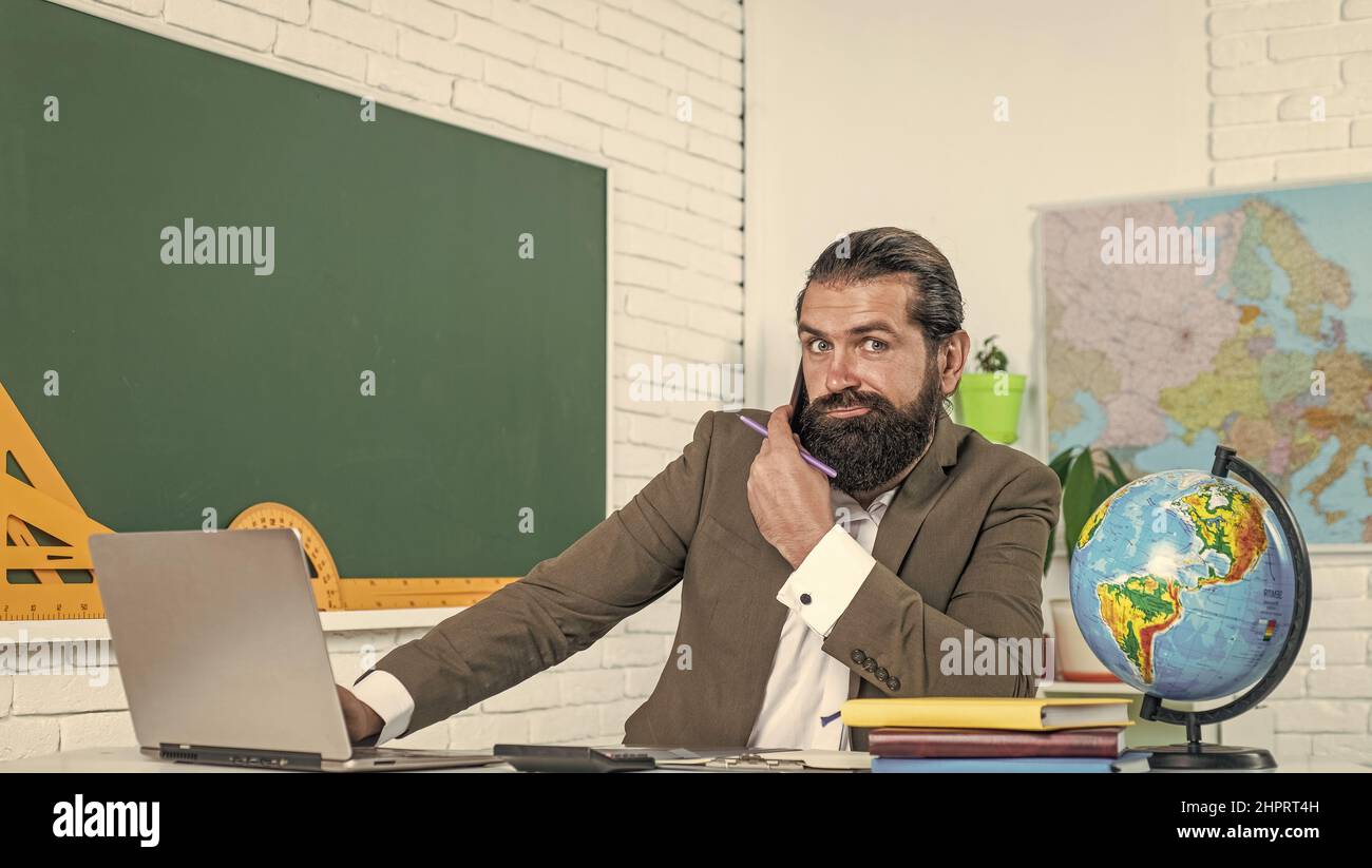 Smiling teacher has phone conversation in classroom, school online ...