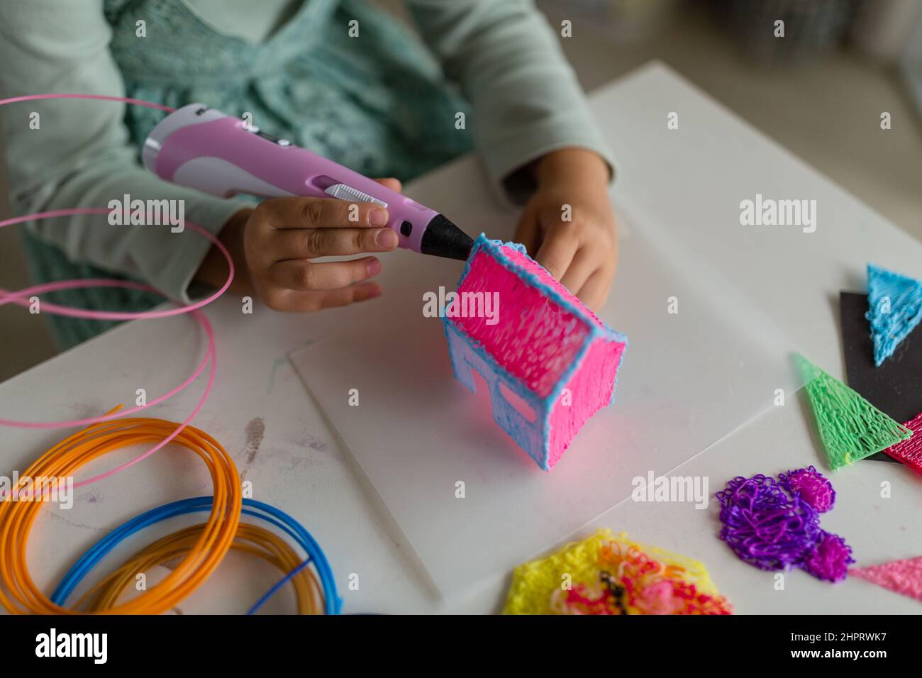 Cute little girl with blonde hair makes a plastic house, draws parts ...