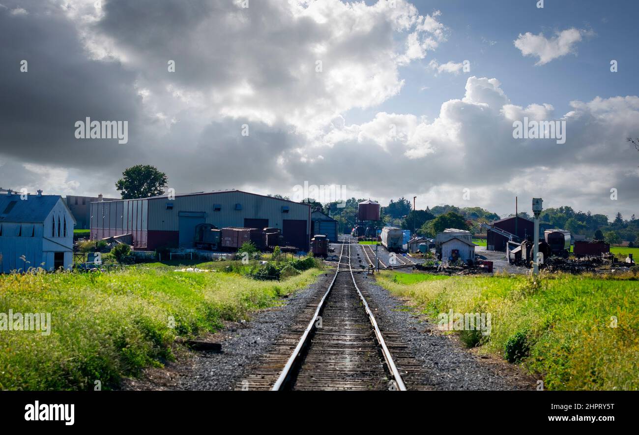 A Single Rail Road Track going into a Freight Yard on a Cloudy Sunny ...