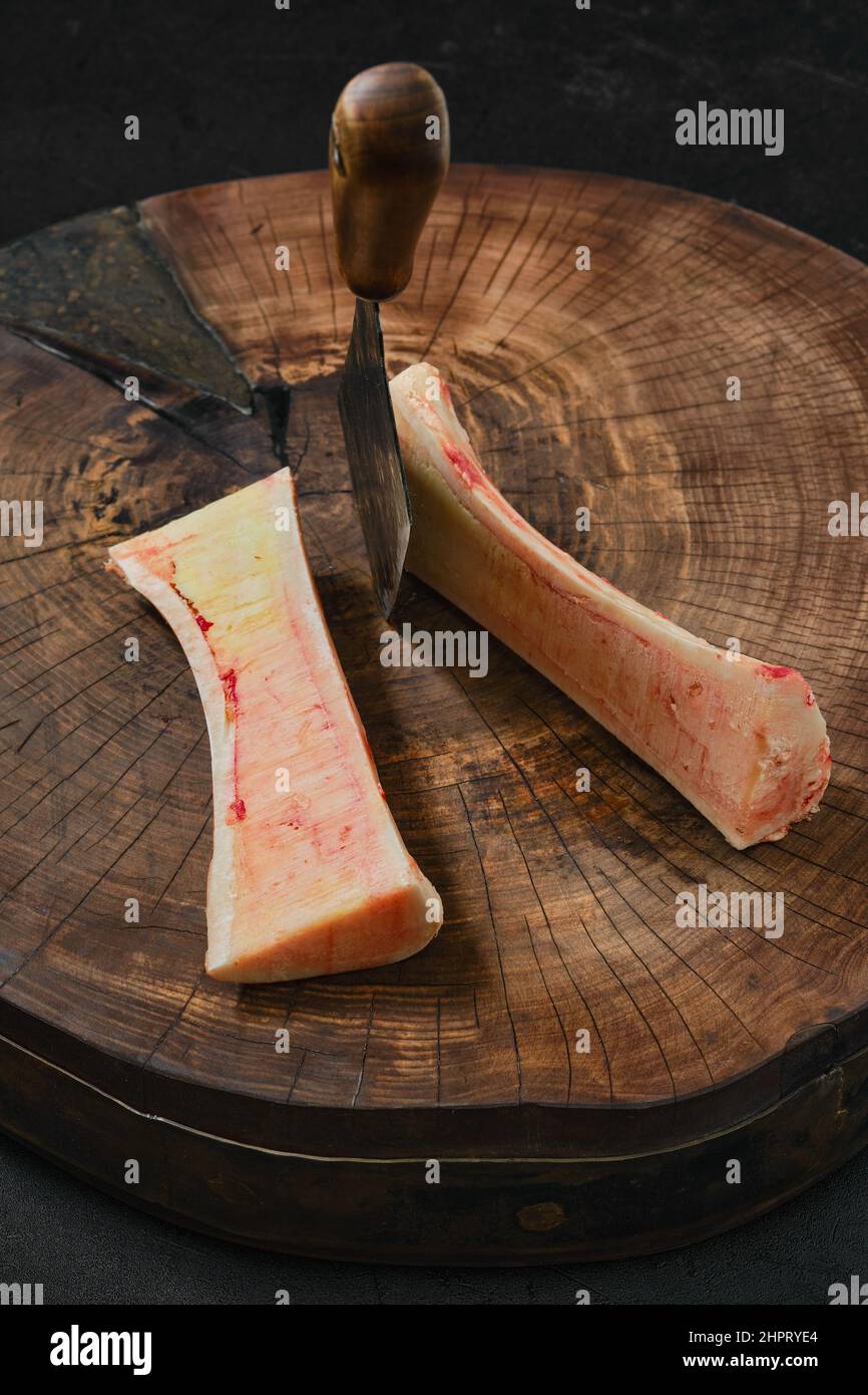 Overhead view of large beef bone marrow chopped with cleaver on half on ...