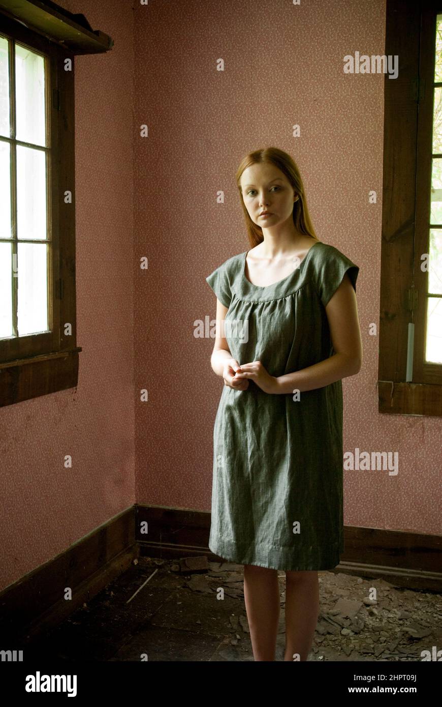 Young woman standing inside old dark wallpapered room Stock Photo - Alamy