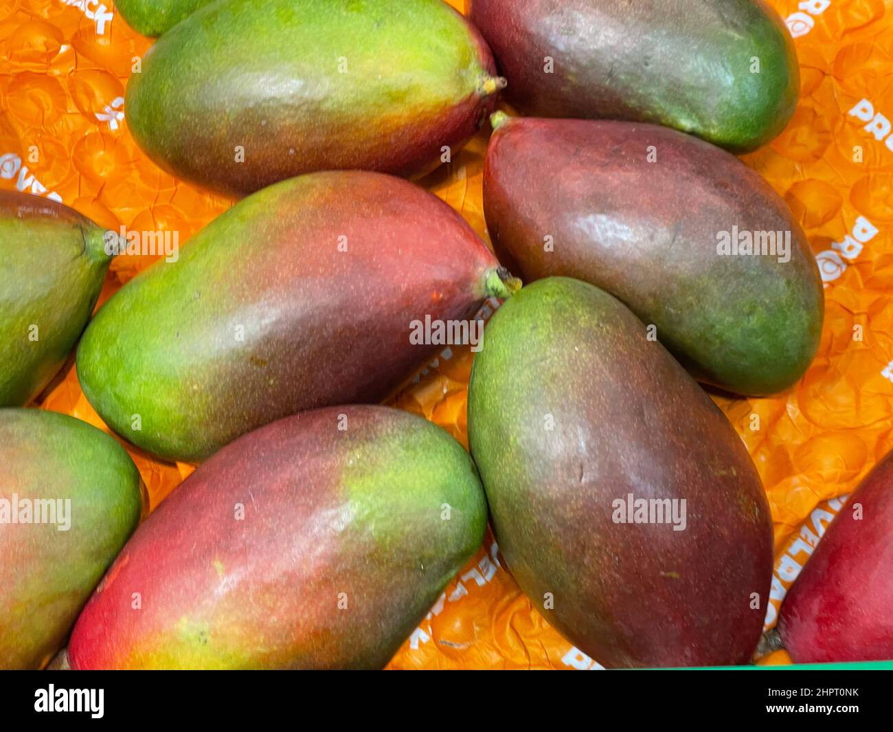 Woman choosing ripe mango at supermarket. Close up Stock Photo - Alamy