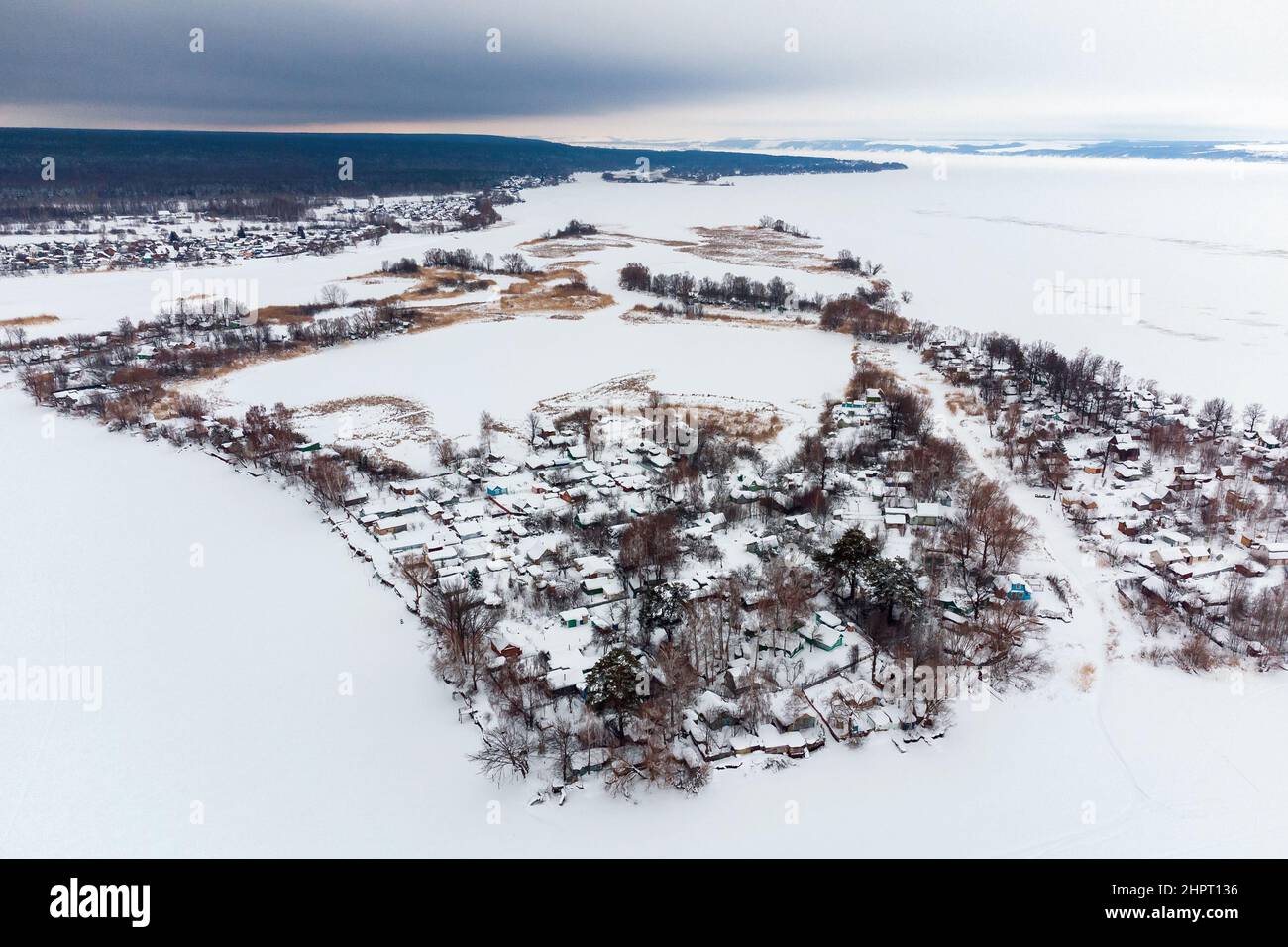 Aerial view of village in middle of frozen bay on winter day after ...