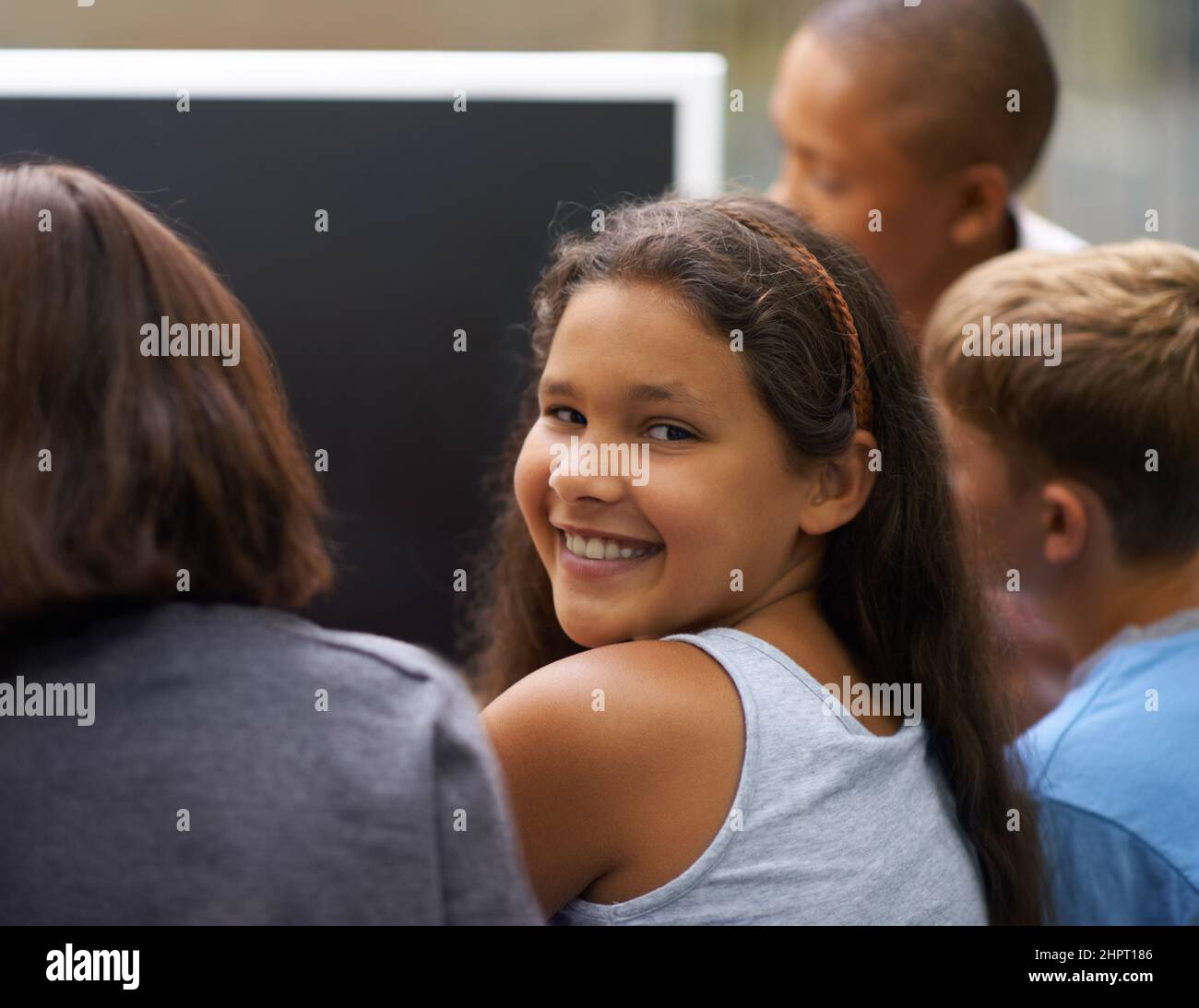 Smiling during computer class. Portrait of a young schoolgirl looking ...