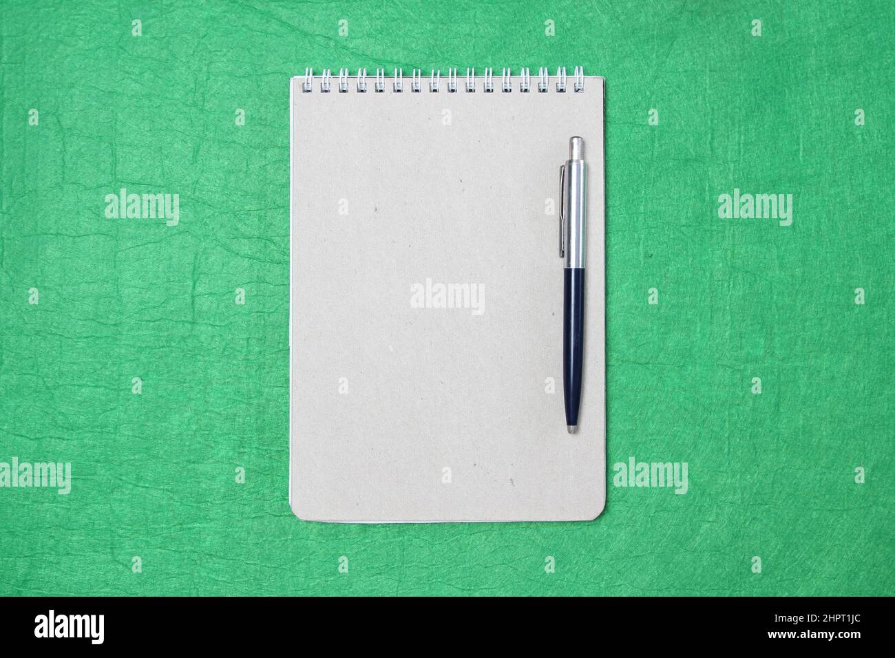 White and gray notepad sheet with spiral with pen against the ...