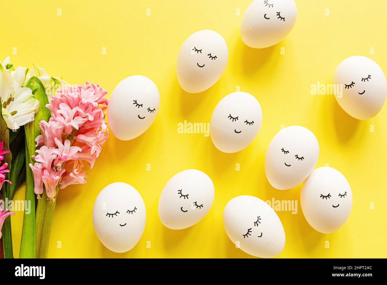 Creative easter eggs with cute face and sleepy eyes on pastel yellow ...