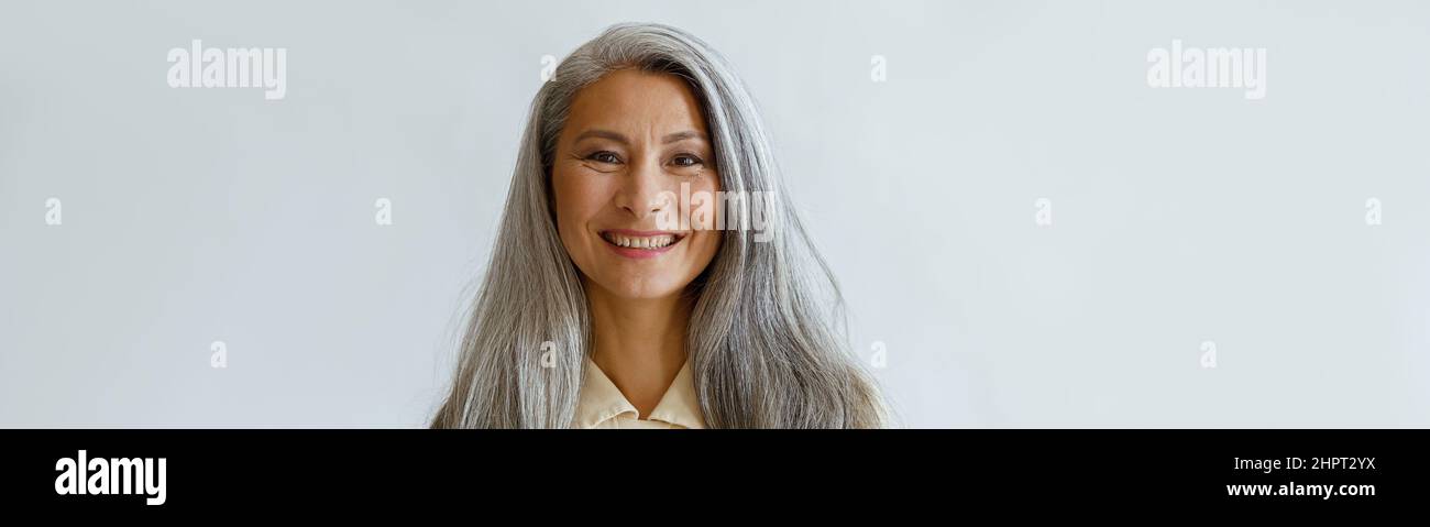 Portrait of smiling Asian woman with hoary hair and crossed arms on ...