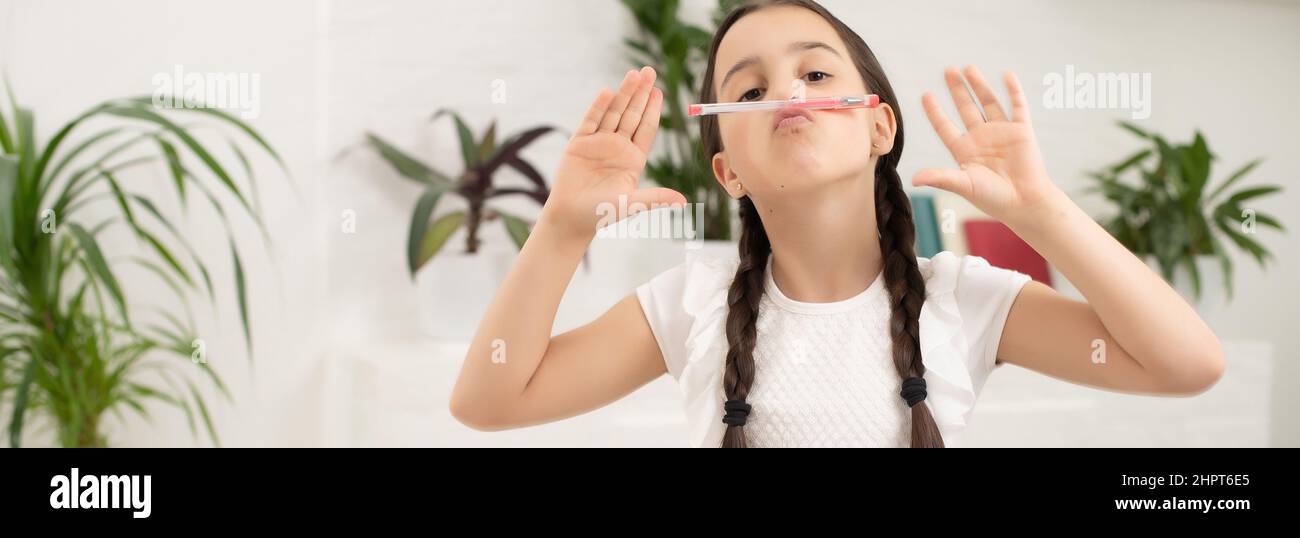 Smart little schoolgirl with pen and books writing a test in a ...