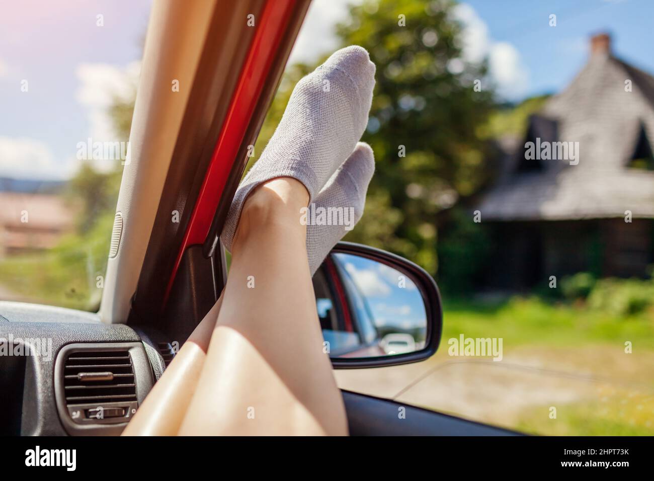 Woman's legs out of car window. Passenger feels free and happy on road ...