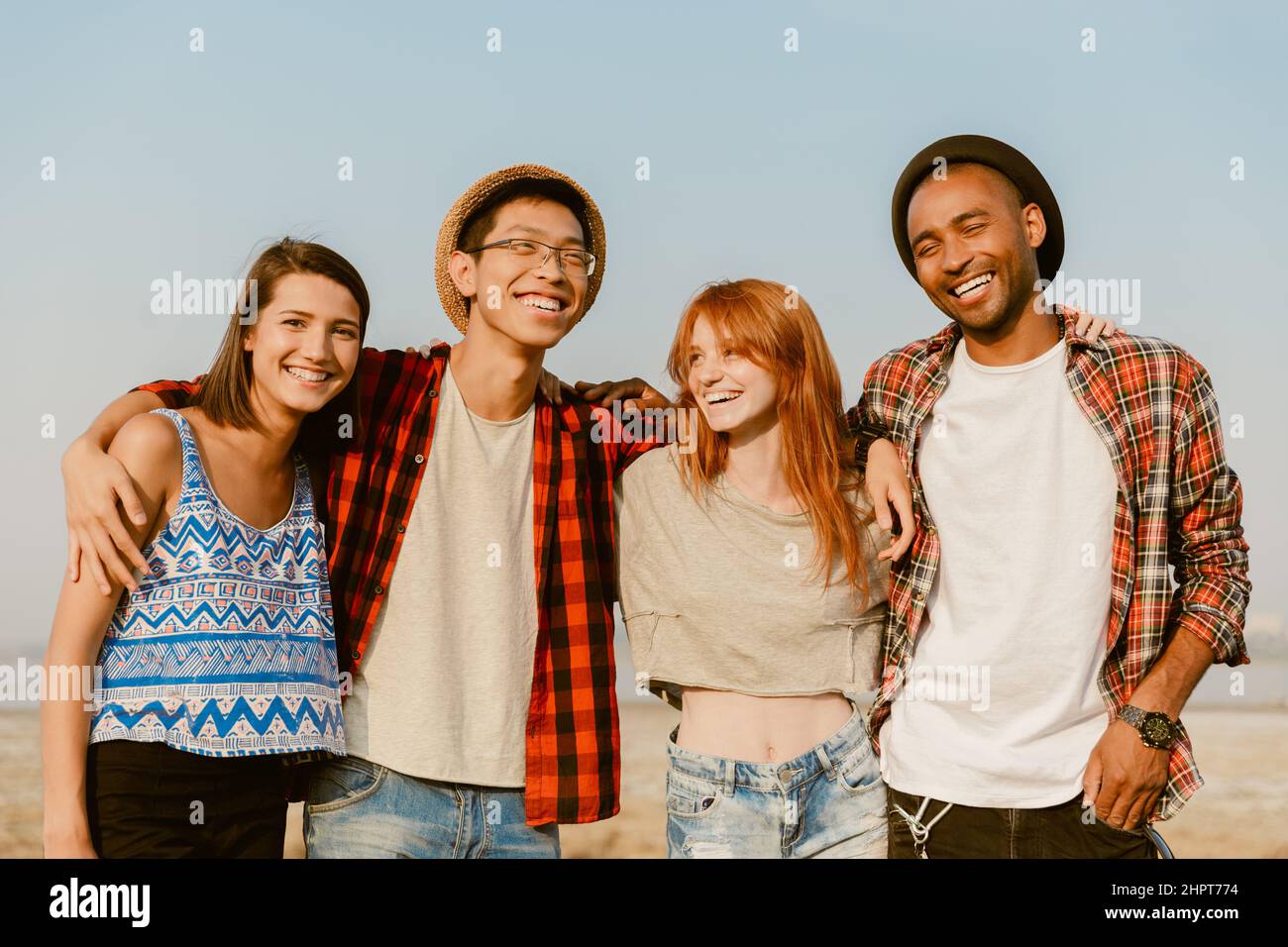 Young multiracial friends hugging and smiling together while posing ...