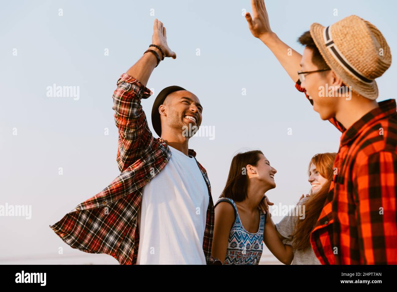 Young multiracial friends making fun while giving high five outdoors ...
