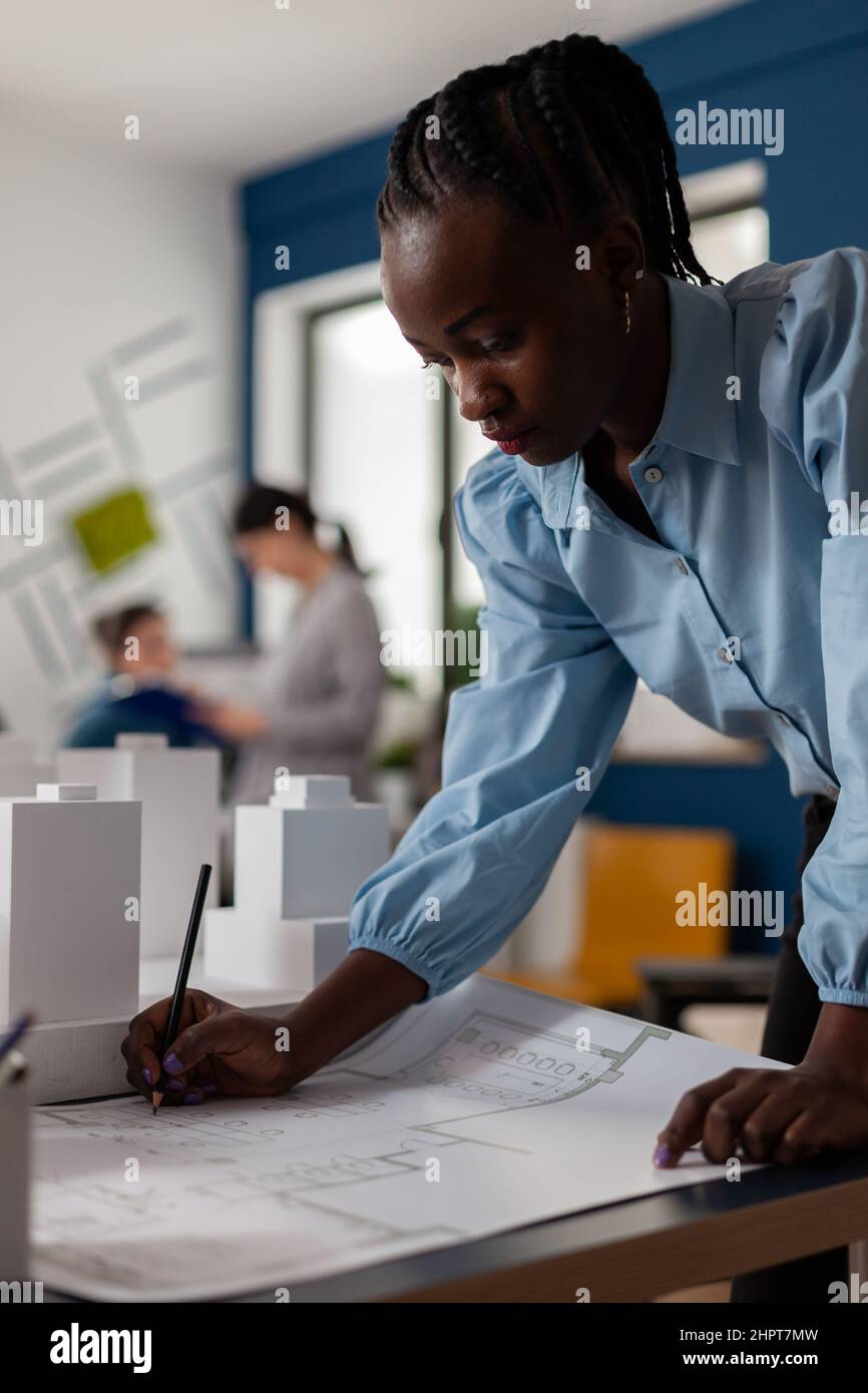 Portrait of architect making notes on construction plan papers at desk ...