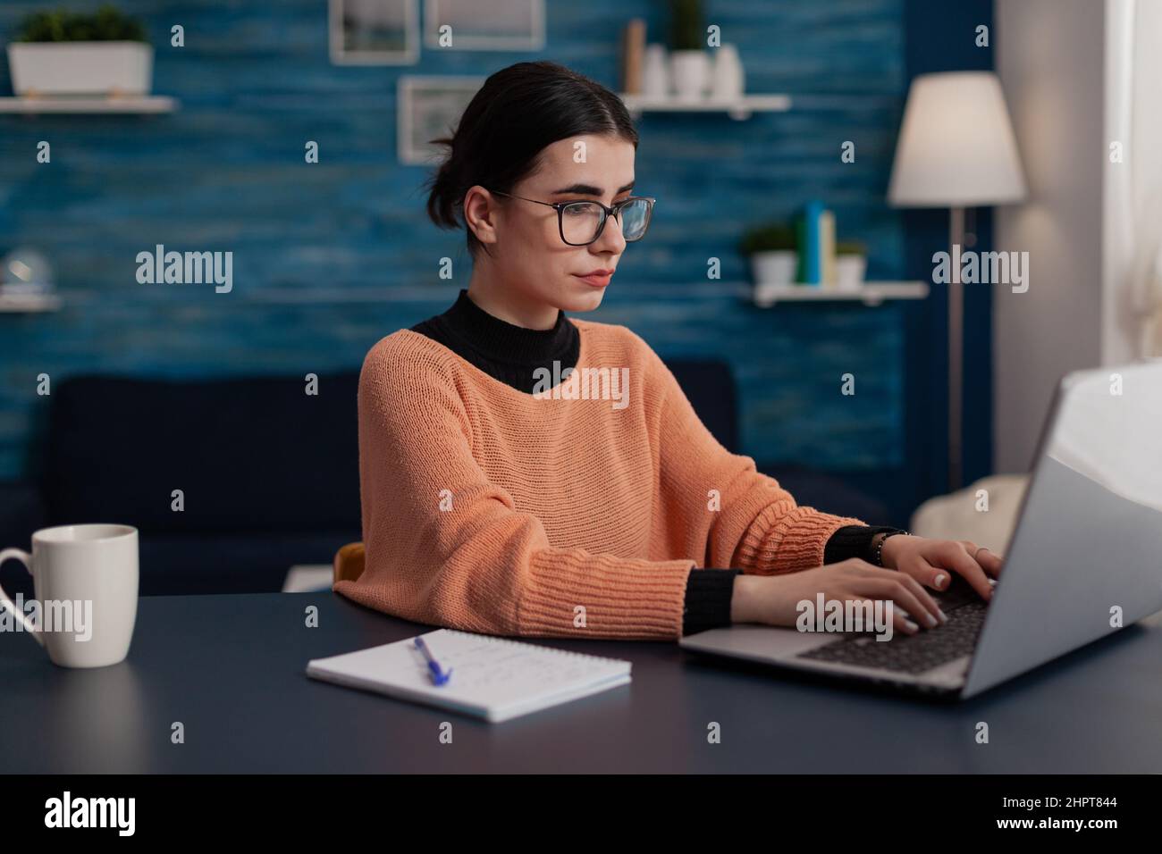 Student with notebook studying remote looking at laptop screen ...
