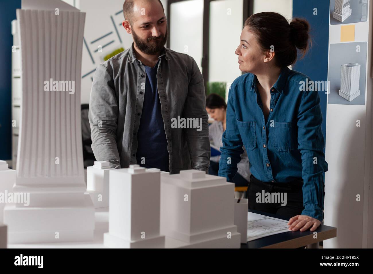 Architects doing teamwork looking at each other discussing blueprints ...