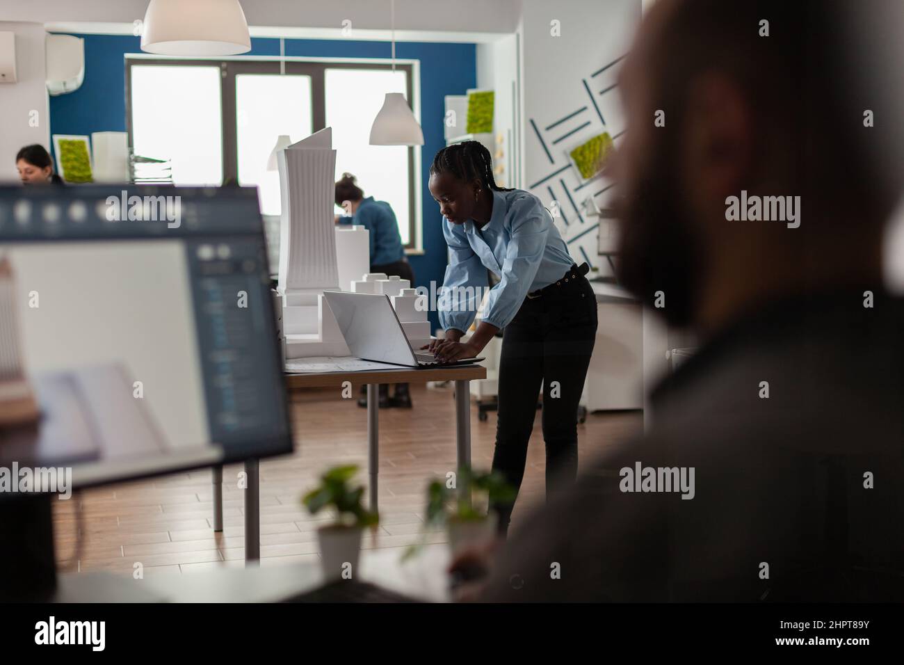 Architect looking at blueprints on laptop at desk with architectural ...