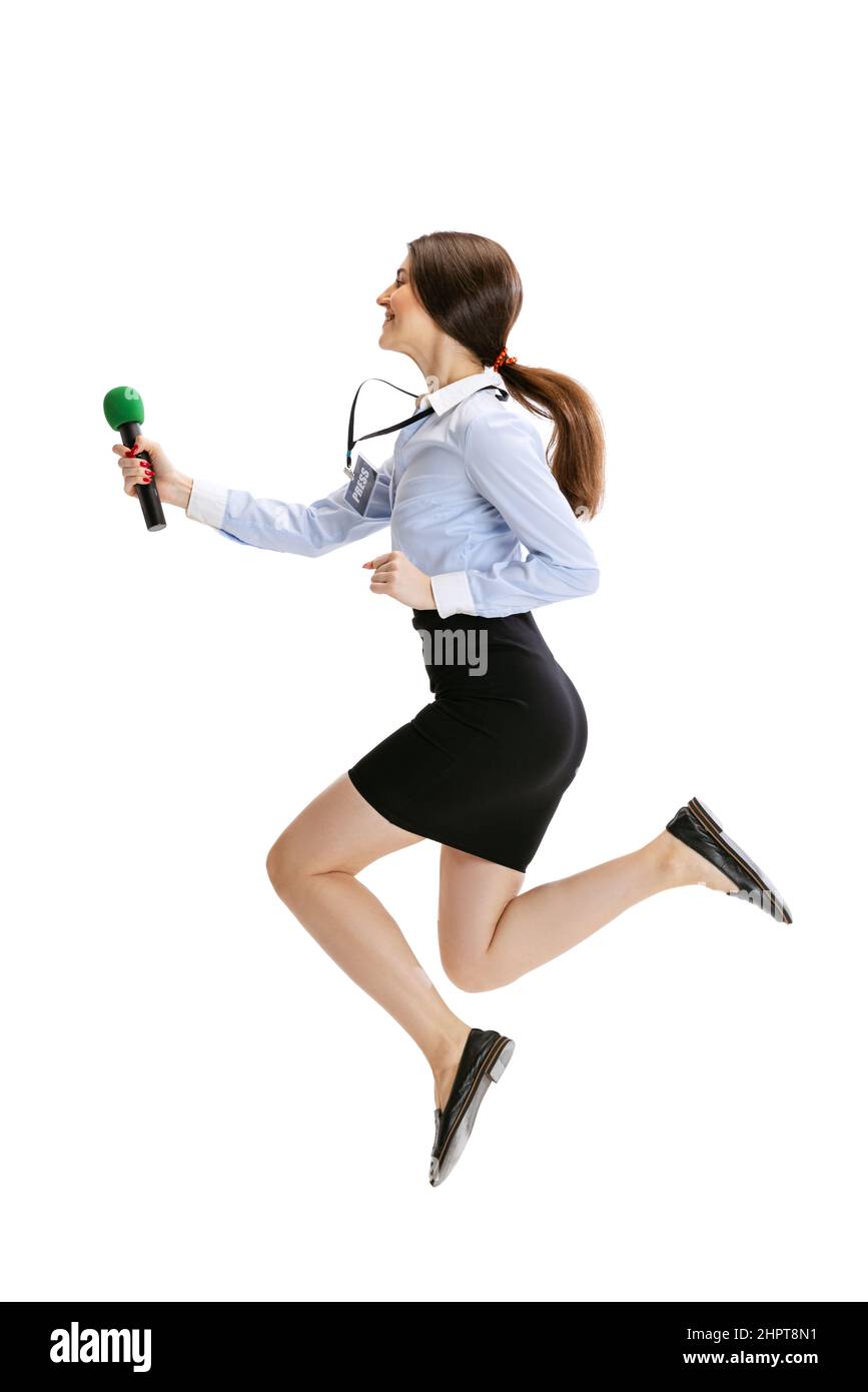 At interview. Female journalist holding reporter microphone jumping isolated on white studio ...