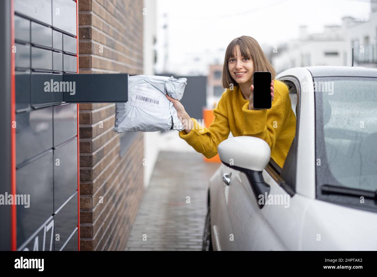 Woman getting parcel from the post office terminal right out of the car ...