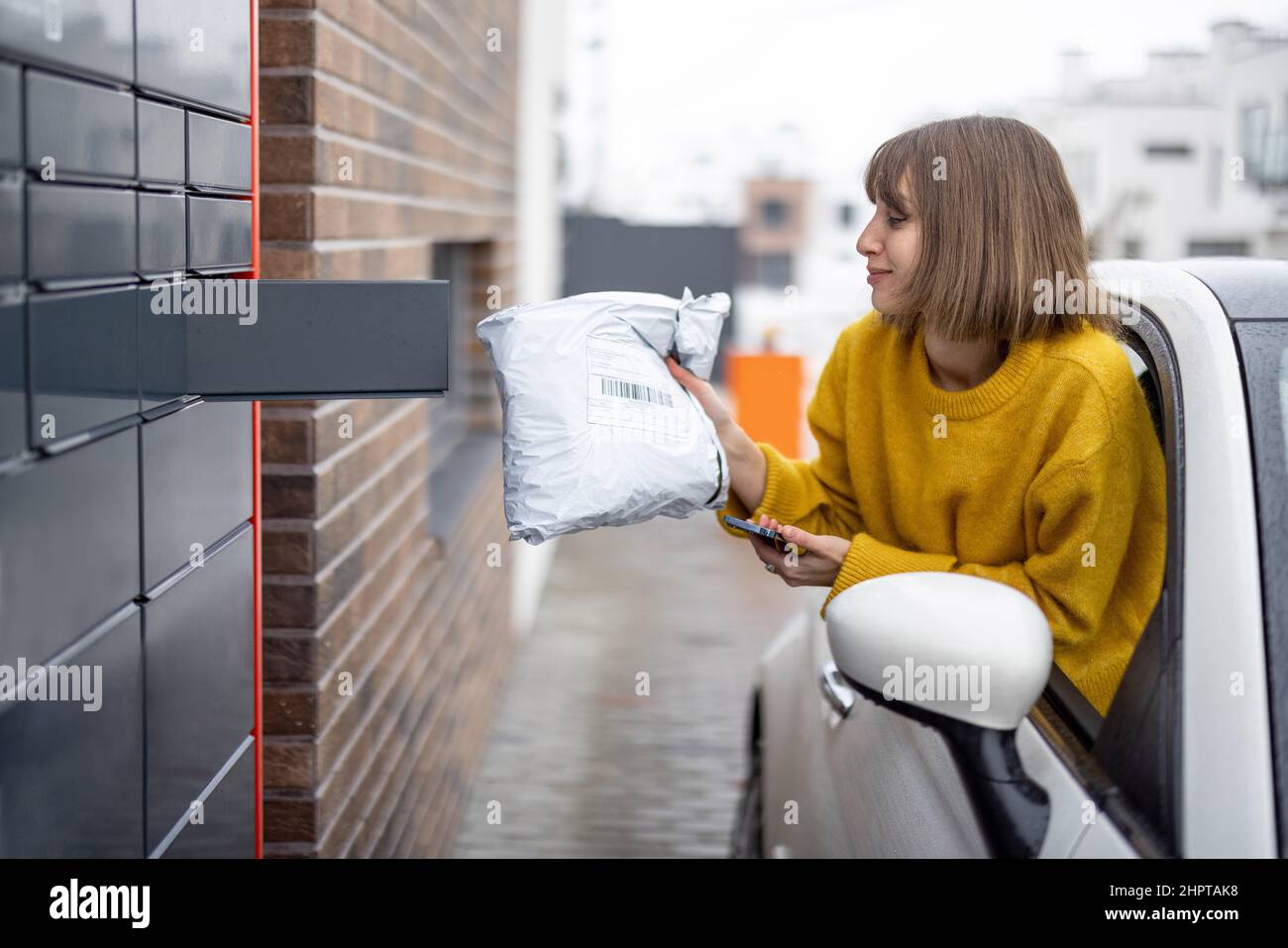 Woman getting parcel from the post office terminal right out of the car ...
