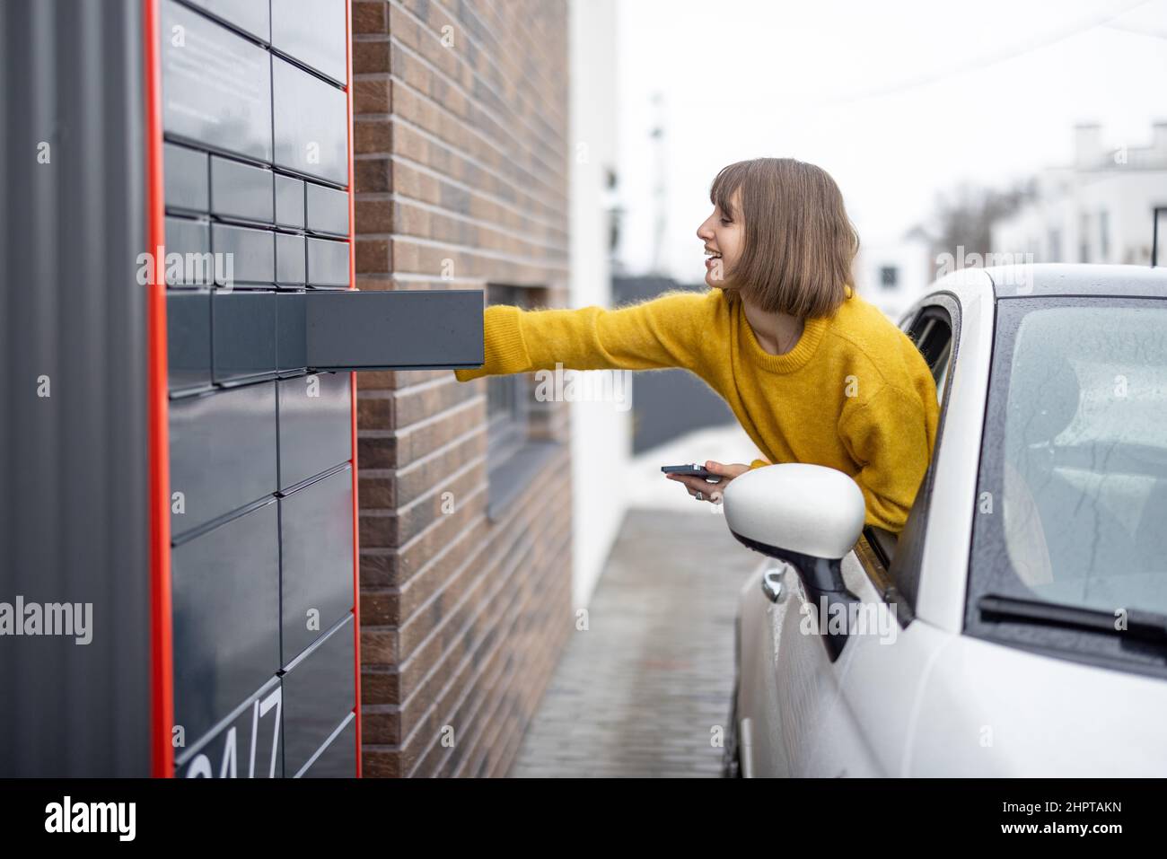Woman getting parcel from the post office terminal right out of the car ...