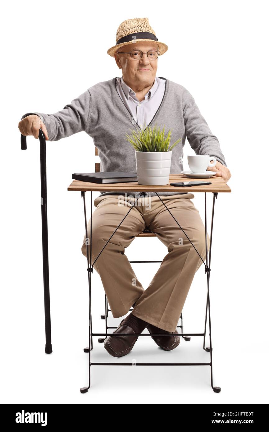 Elderly man sitting at a wooden coffee table isolated on white ...