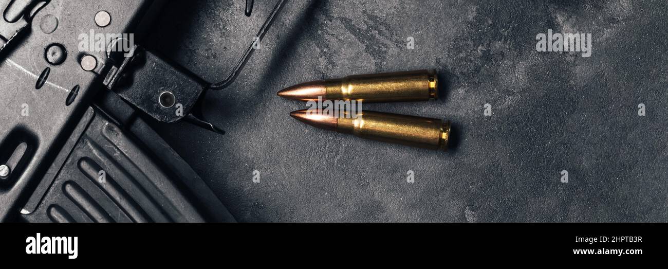 Two bullets and Kalashnikov assault rifle on gray concrete background ...