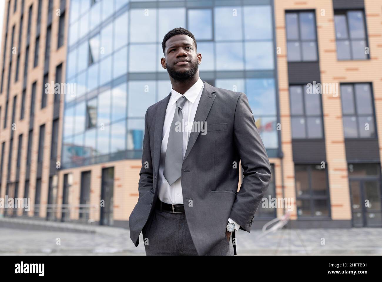 Young black man manager in suit holding hands in trousers pockets ...