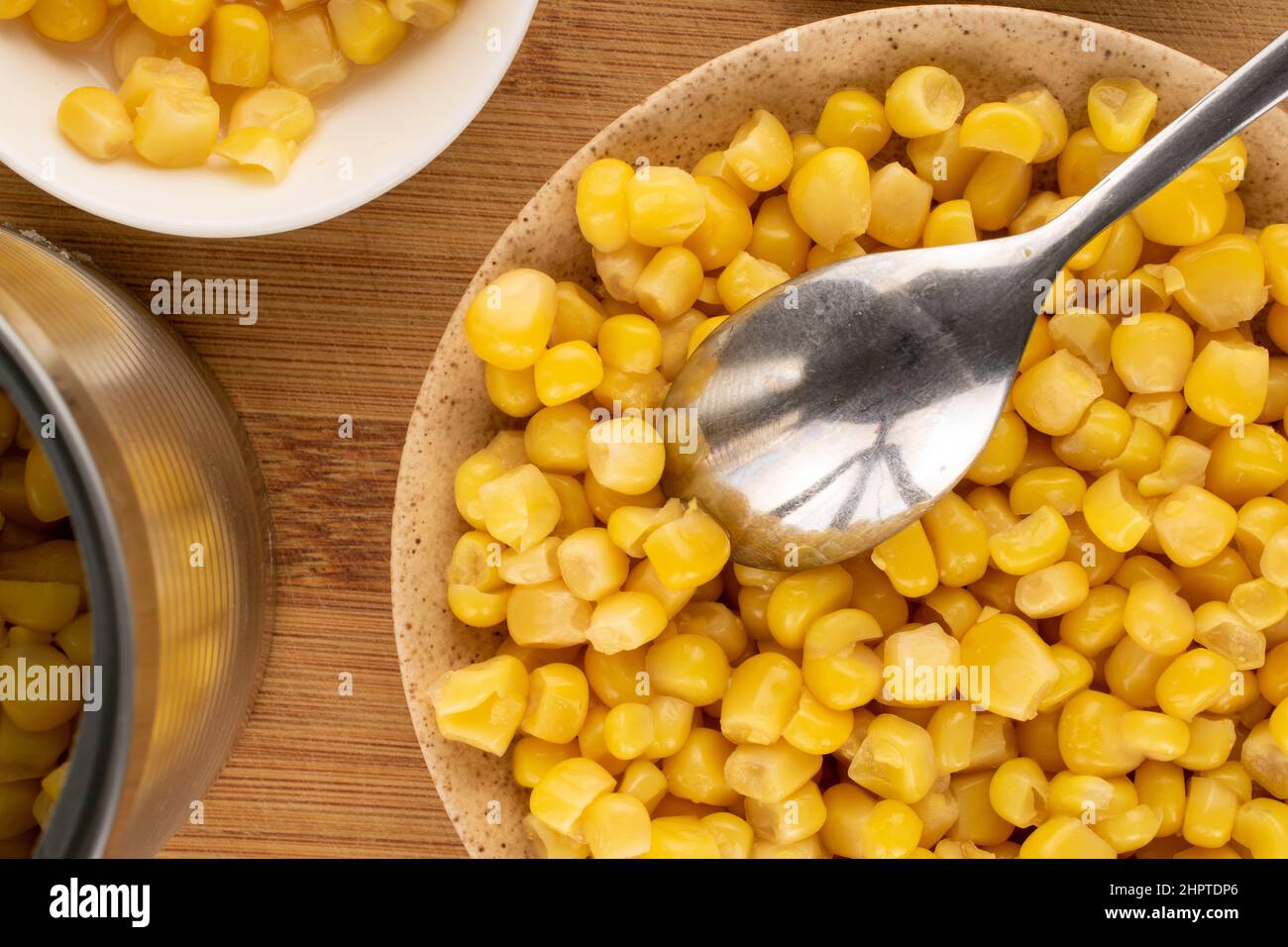 Bright yellow sweet kernels of canned corn in a ceramic dish and metal ...