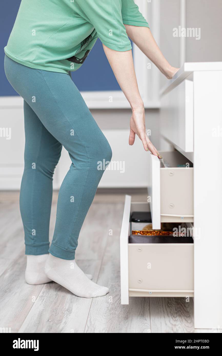 woman pulls out a drawer in a chest of drawers at home. High quality ...