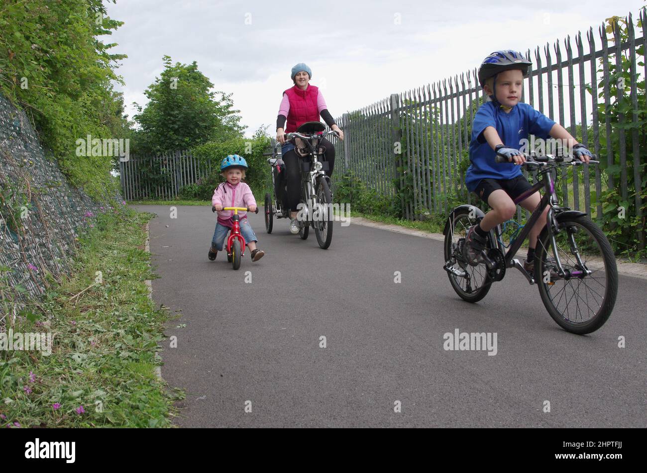 Mother cycling and guiding young children on cycle path Stock Photo - Alamy