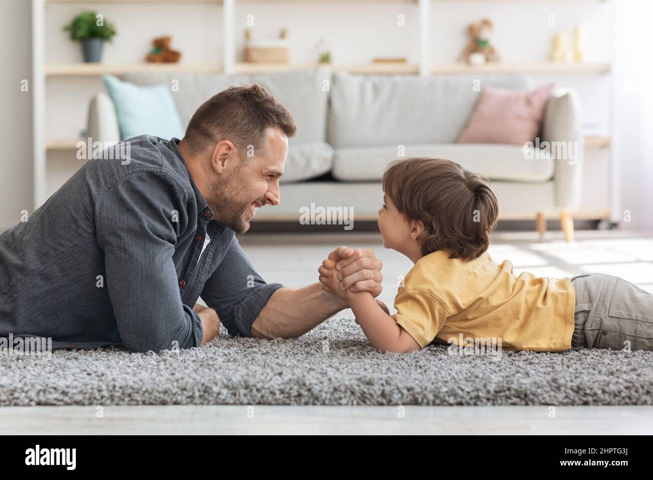 Bringing up strong kid. Happy father competing arm wrestling match with ...