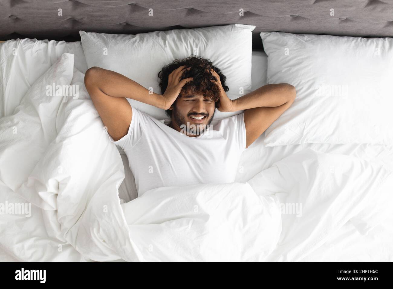 Sick indian guy suffering from headache, laying in bed Stock Photo - Alamy