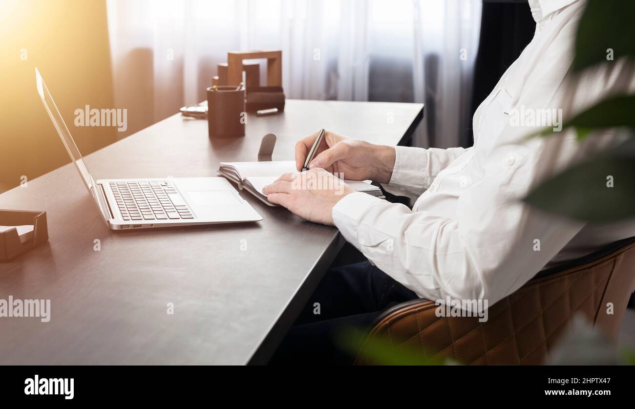 Hands taking notes, writing in planner at office desk with laptop Stock ...