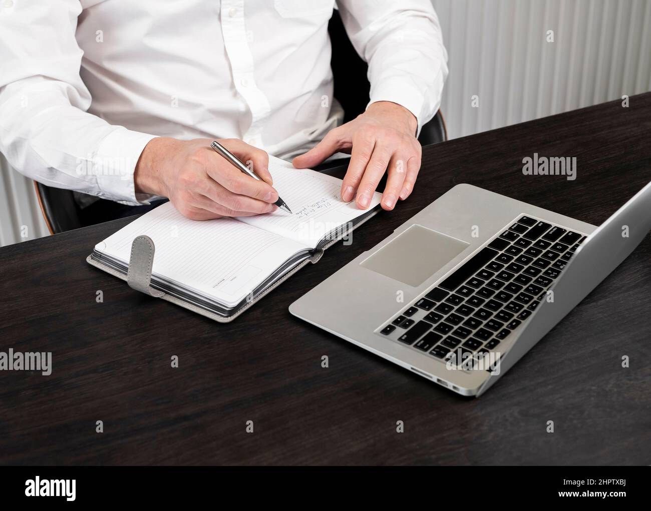 Hands taking notes, writing in planner at office desk with laptop Stock ...
