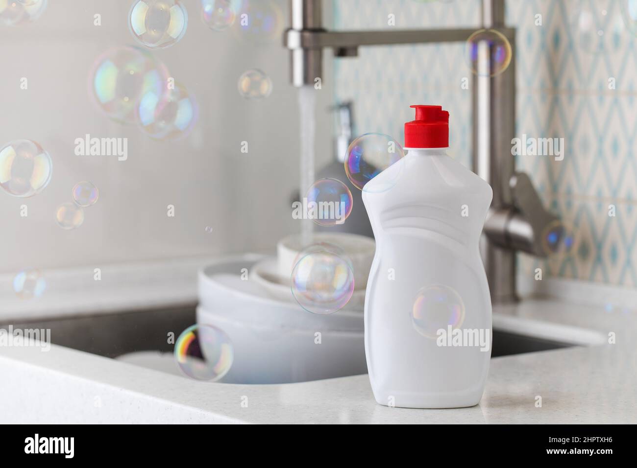White Bottle With Dishwashing Gel With Soap Bubbles Around On The Background Of A Sink With
