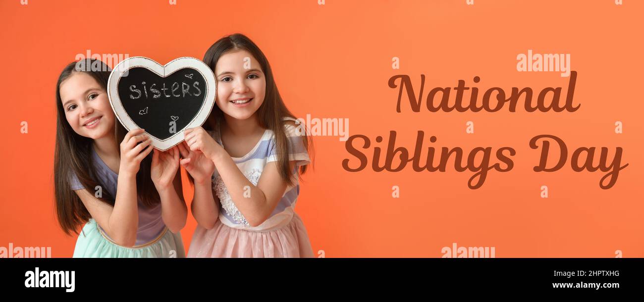 Cute twin girls and board with word SISTERS on orange background ...