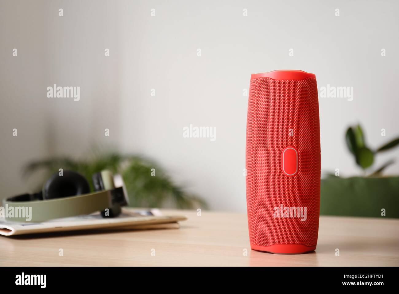 Modern wireless portable speaker, magazines and headphones on table in ...