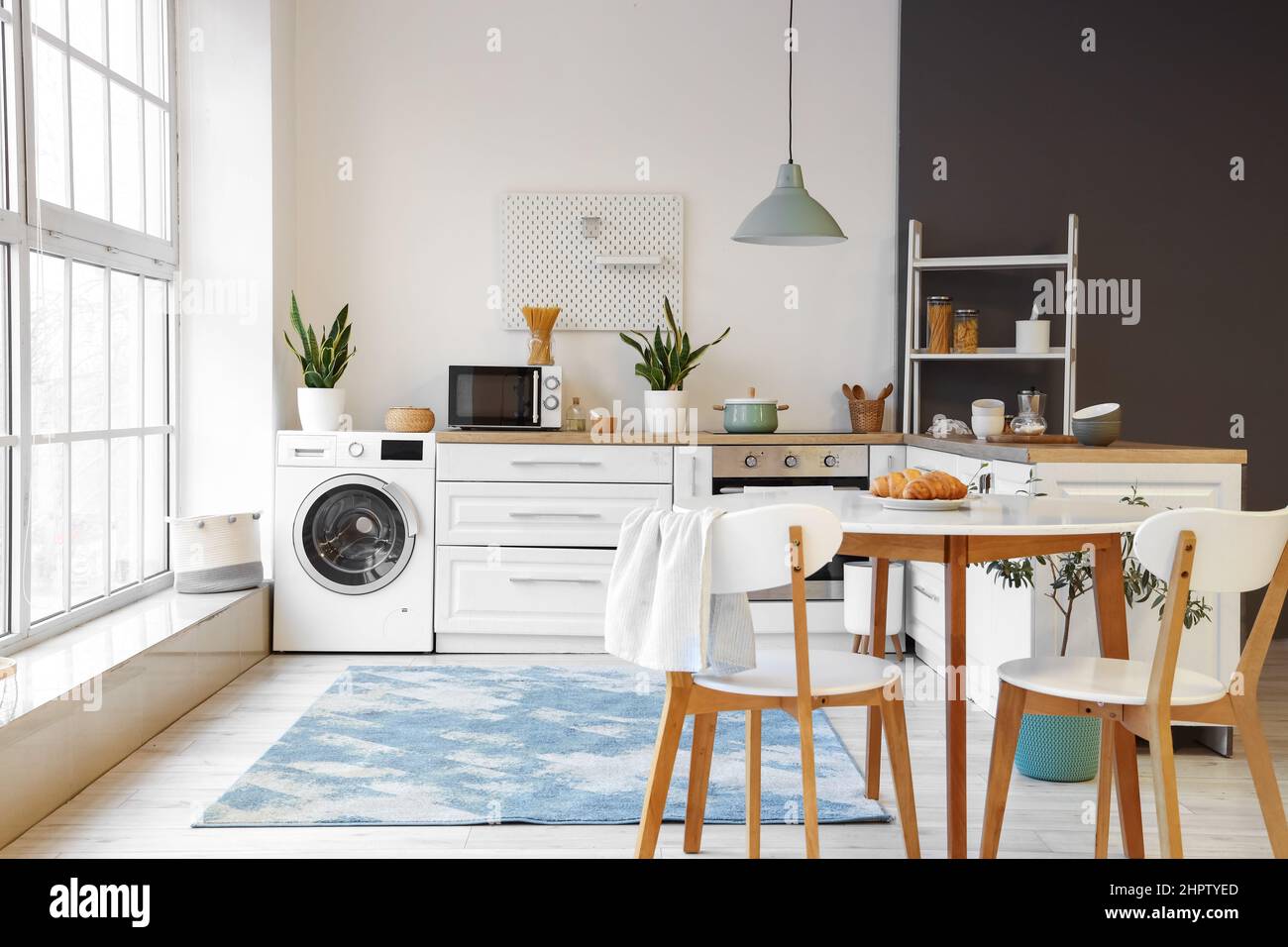 Interior of modern kitchen with washing machine, white counters and ...